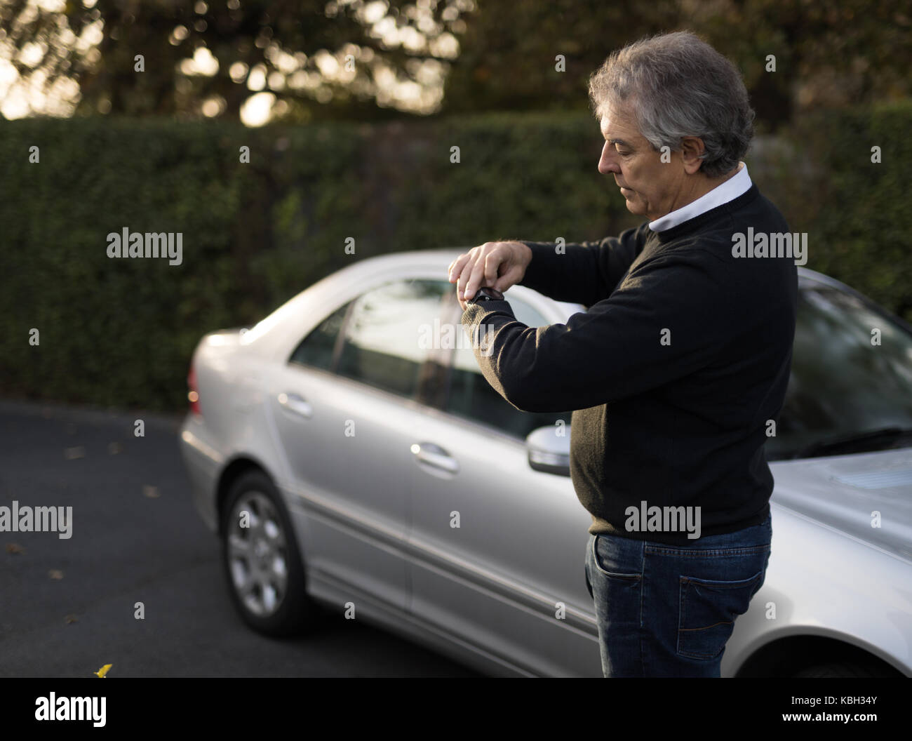 Senior man checking time on his watch on the road Stock Photo - Alamy