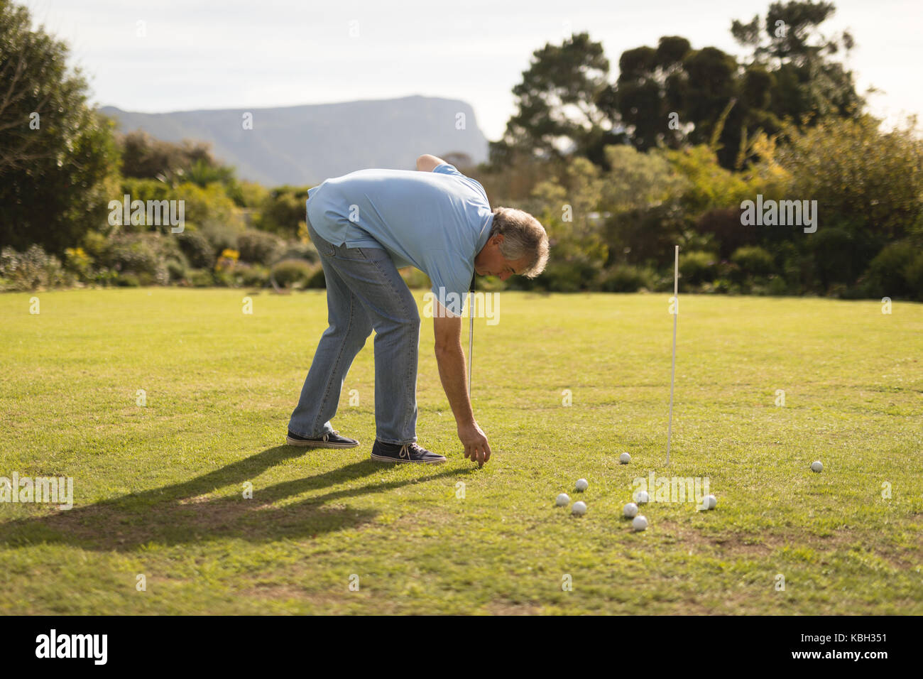 Senior man placing golf ball in golf course Stock Photo - Alamy