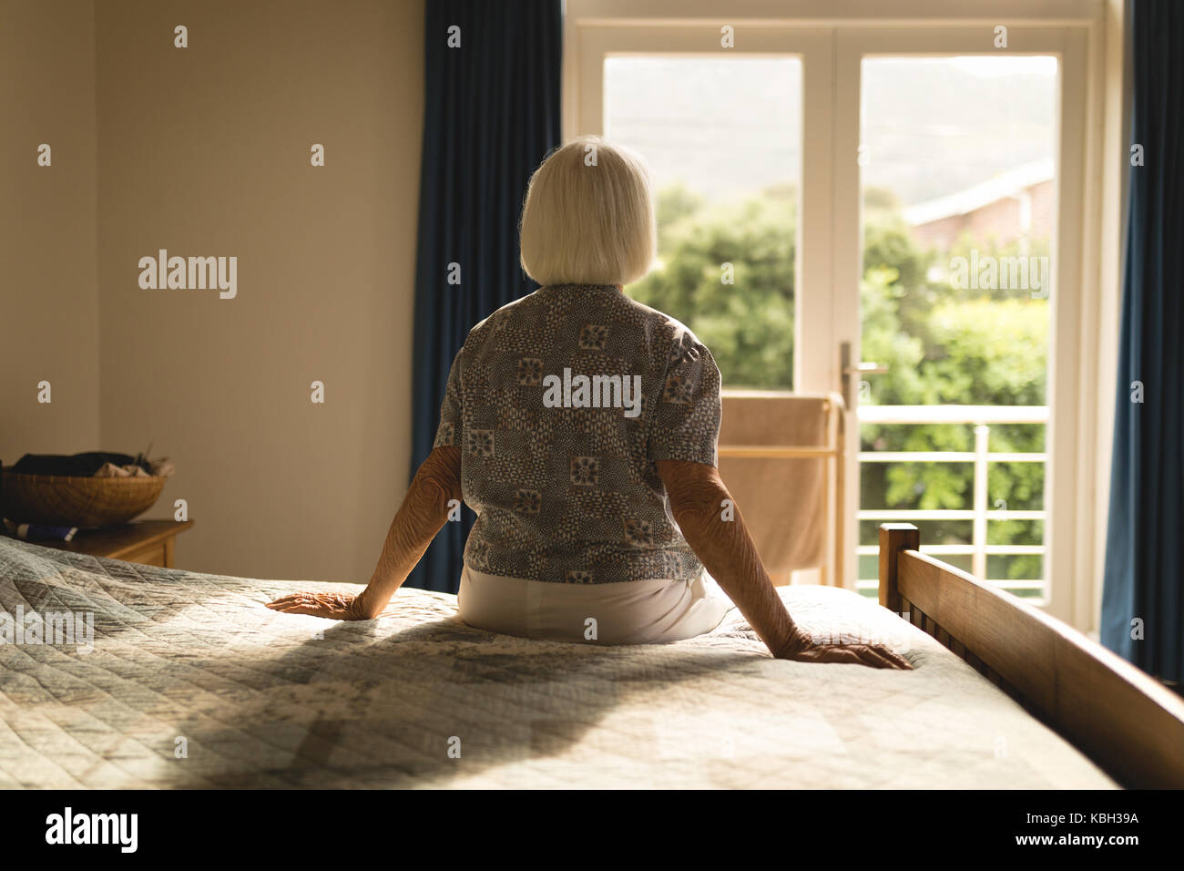 Rear view of senior woman sitting on bed in bedroom Stock Photo - Alamy