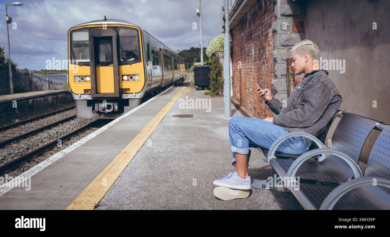 Man using mobile phone at railway platform Stock Photo - Alamy