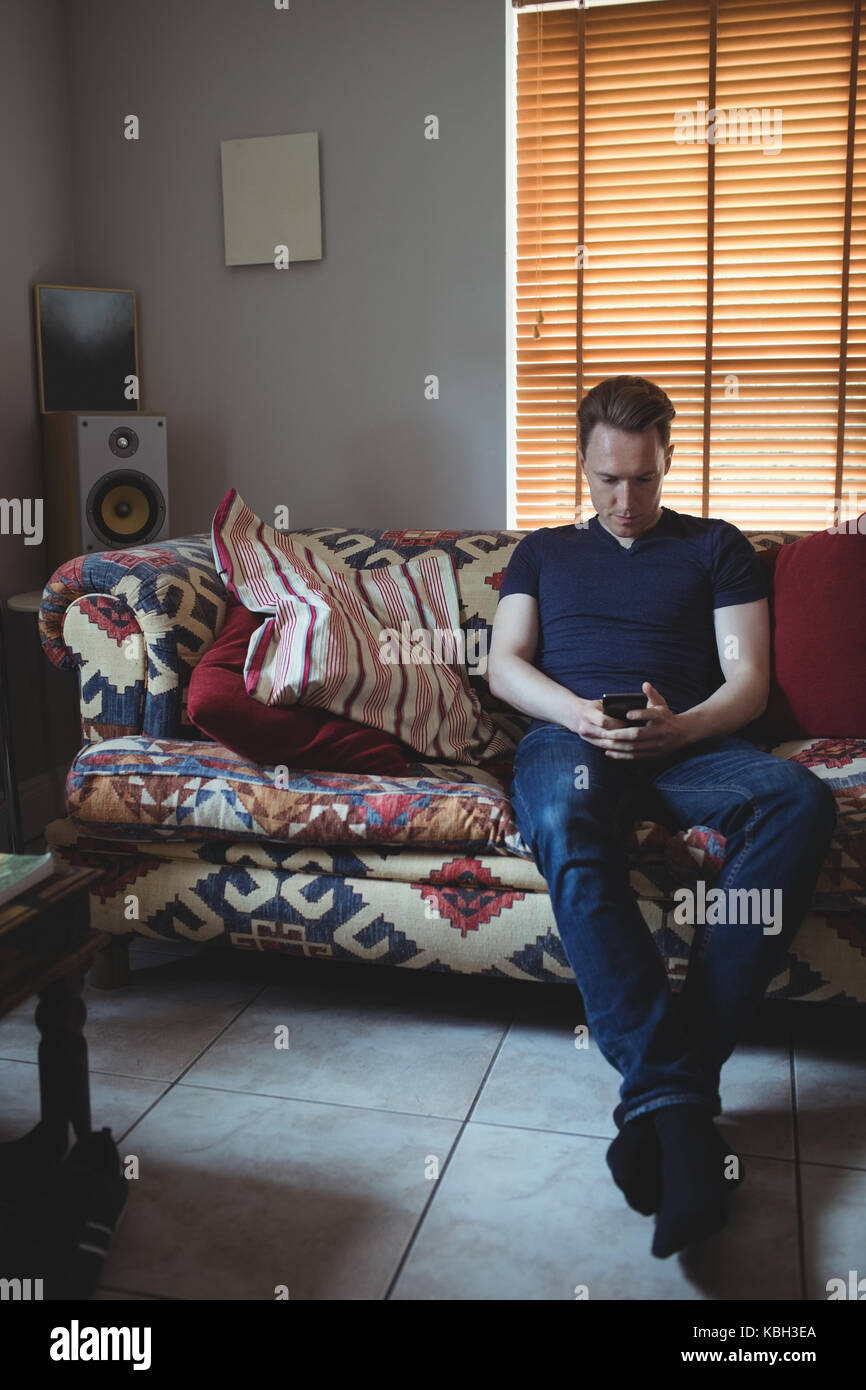 Man using mobile phone in living room at home Stock Photo - Alamy
