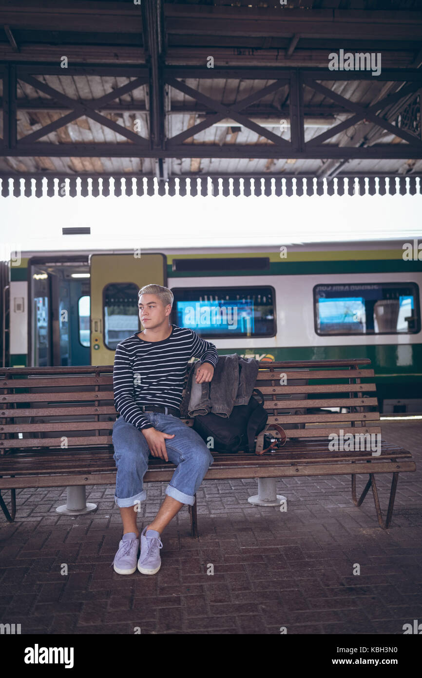 Thoughtful man sitting on bench at railway station Stock Photo - Alamy