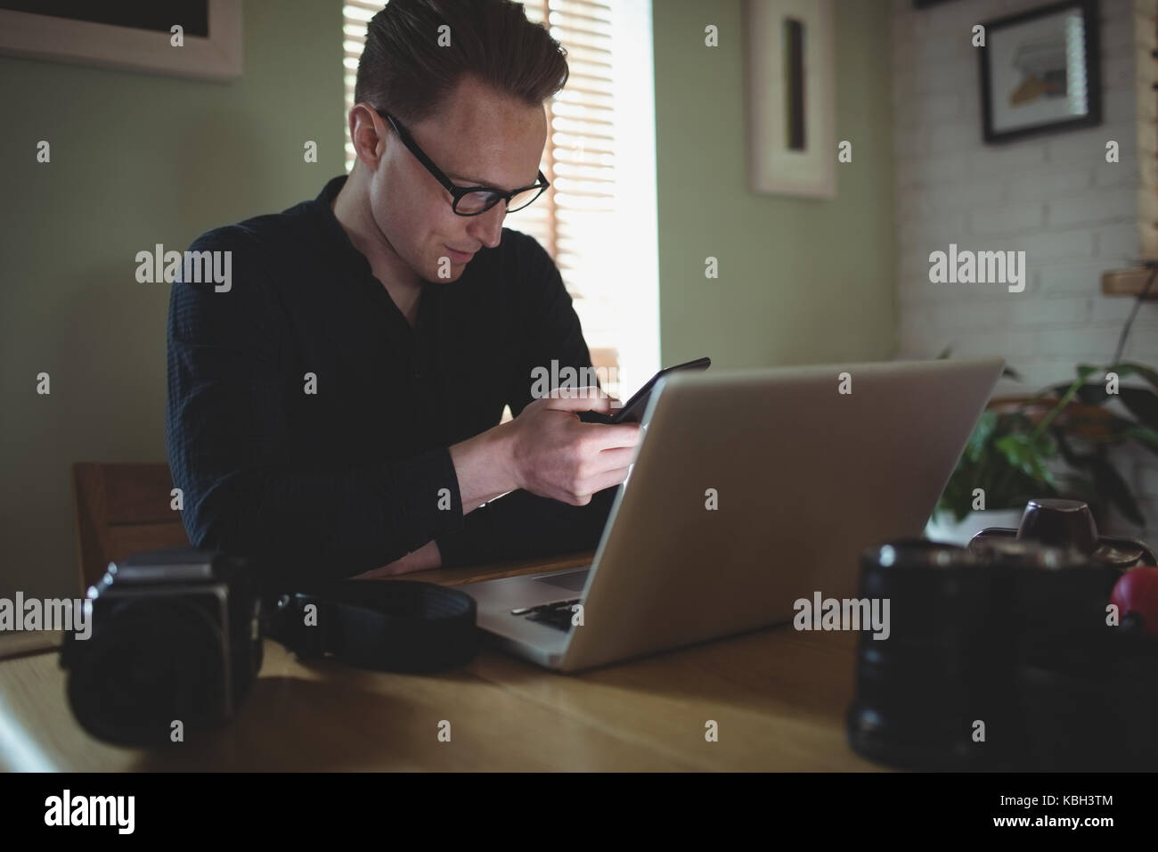Attentive man at desk using mobile phone and laptop Stock Photo - Alamy