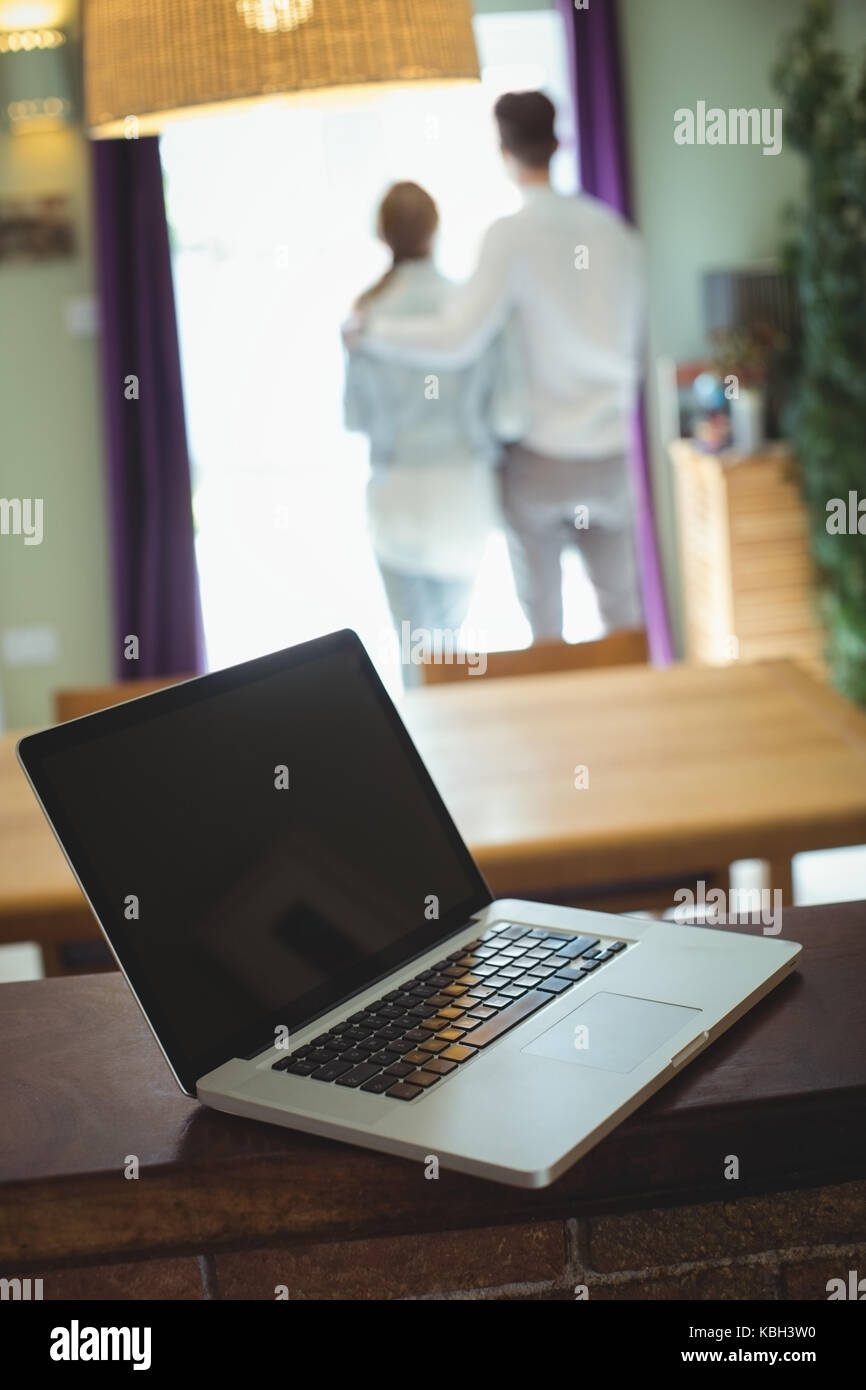View of laptop on wooden table while couple in background Stock Photo ...