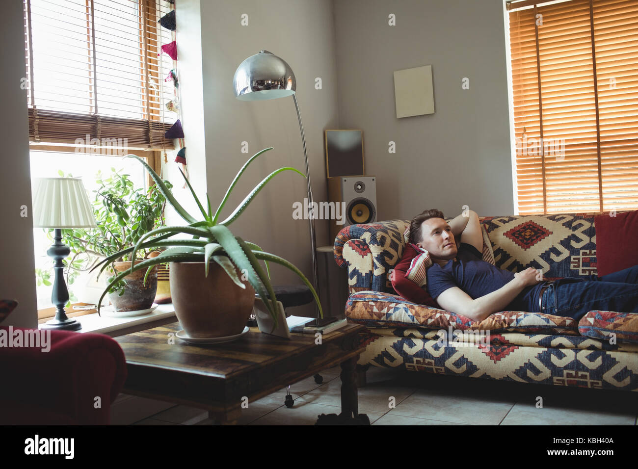 Man relaxing on sofa in living room at home Stock Photo - Alamy