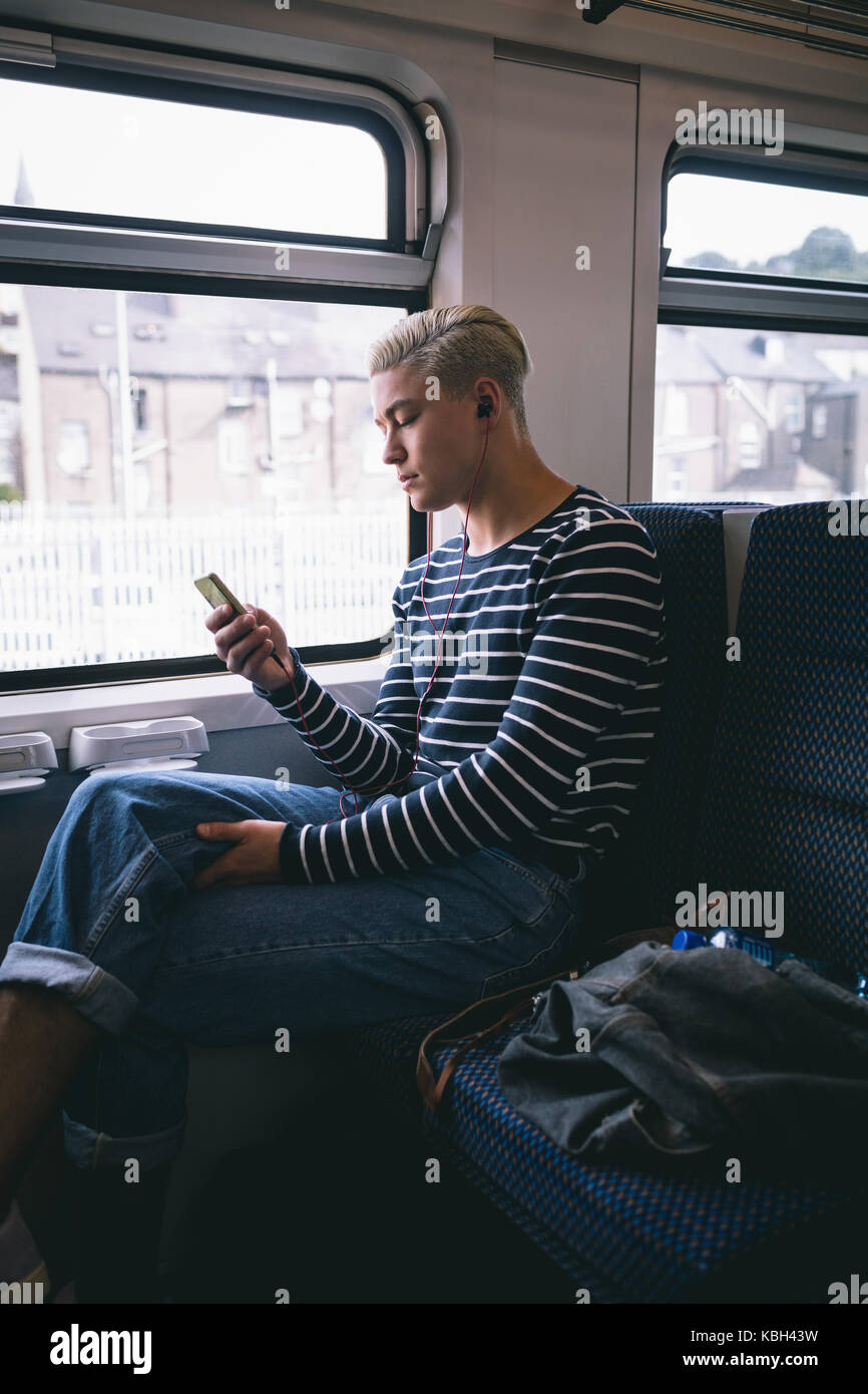 Handsome man using mobile phone while traveling in metro Stock Photo ...