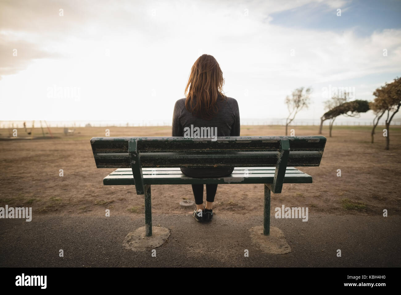 Rear view of thoughtful woman sitting on bench Stock Photo - Alamy
