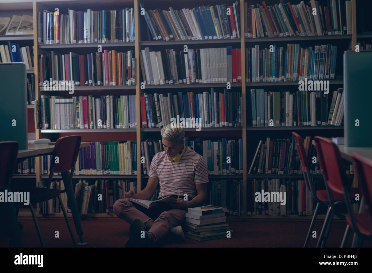 Attentive man reading books in library Stock Photo - Alamy