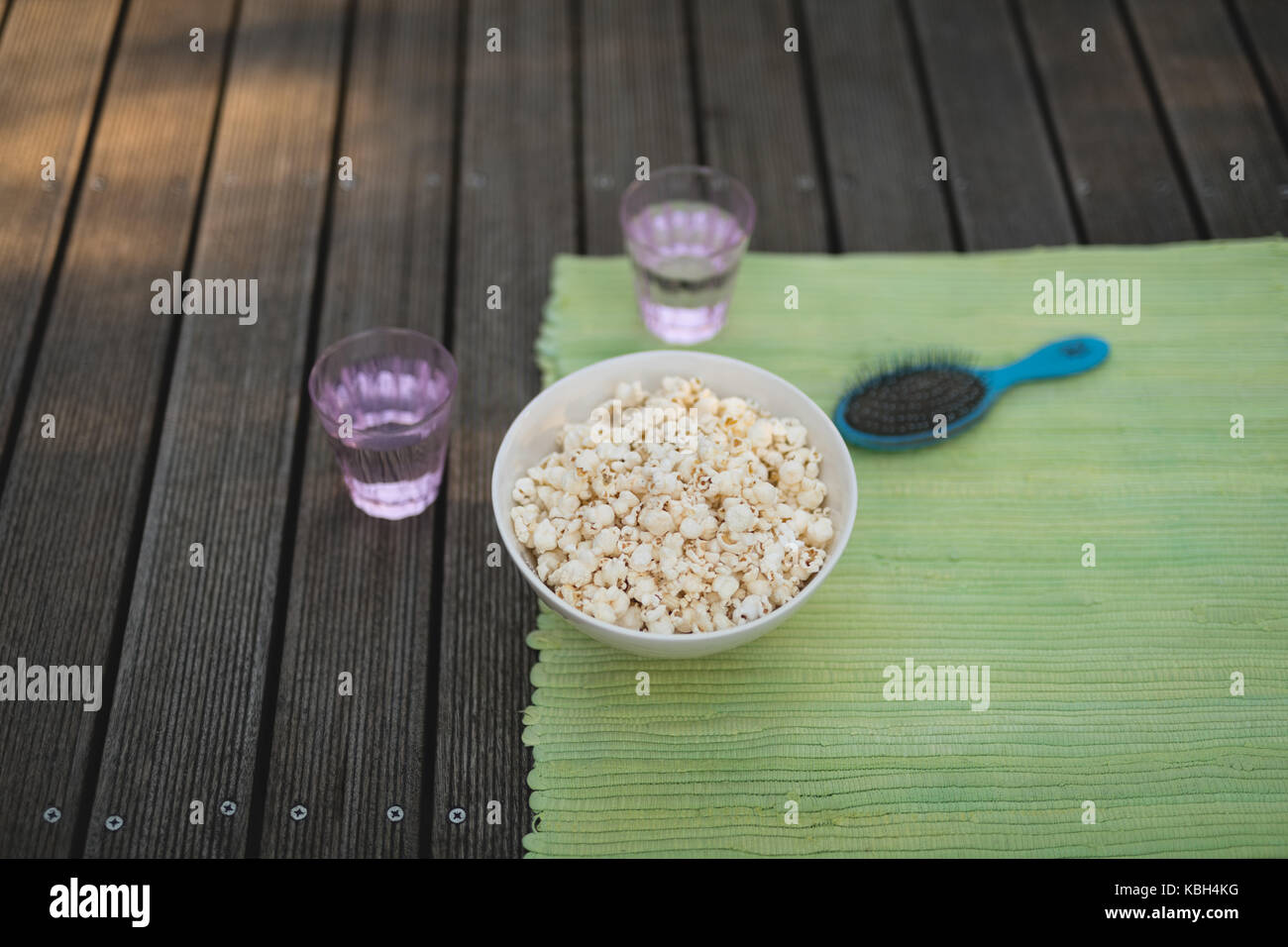Bowl of popcorn, hair brush and glasses of water on wooden plank Stock ...