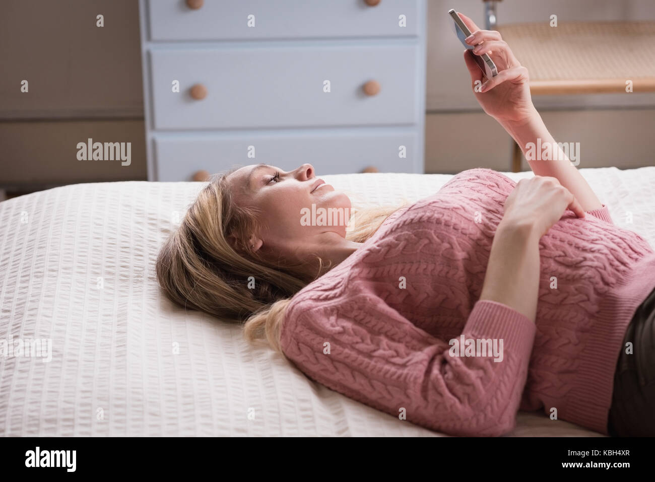 Young woman lying down looking at phone hi-res stock photography and ...