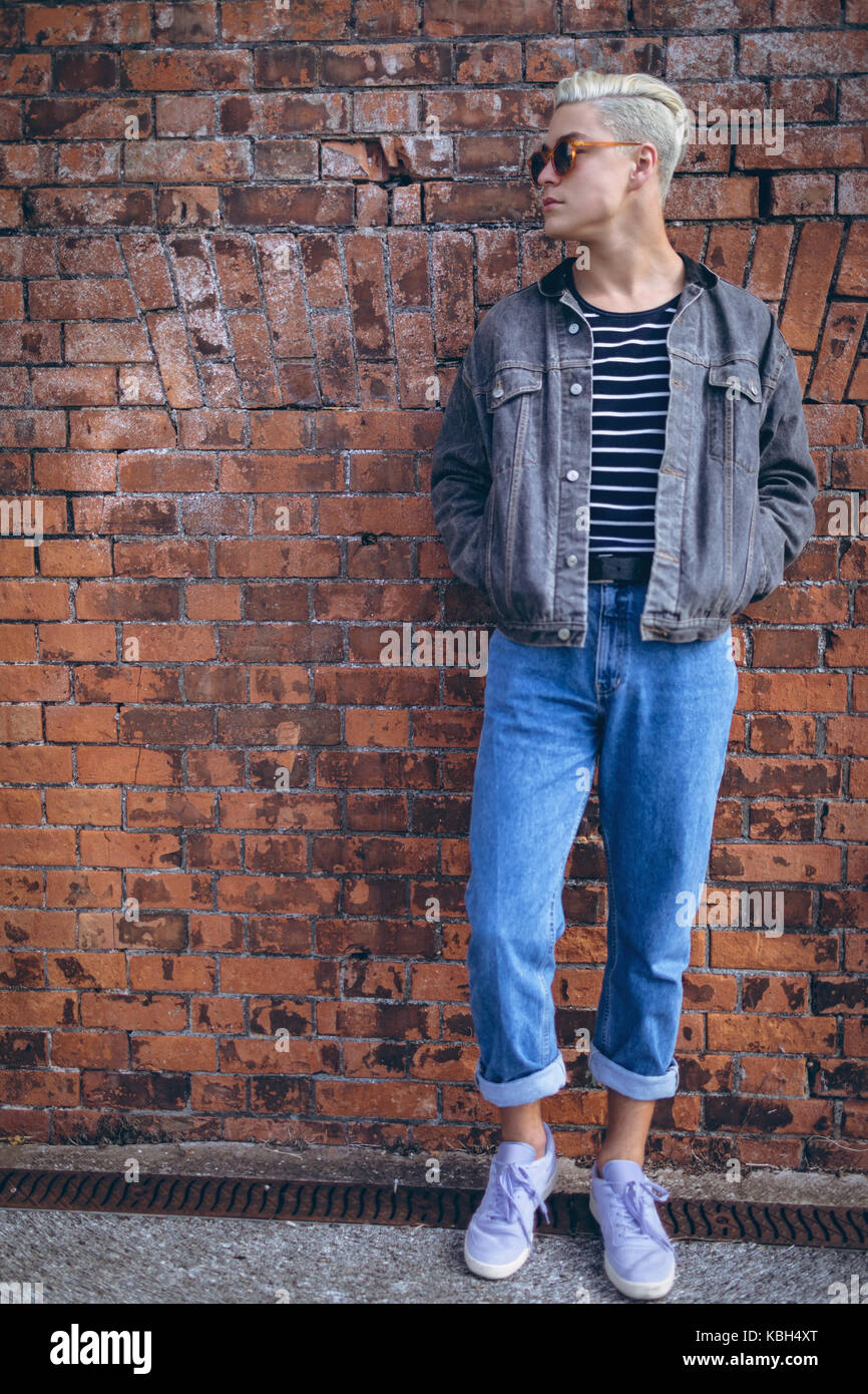 Stylish man posing against brick wall Stock Photo - Alamy