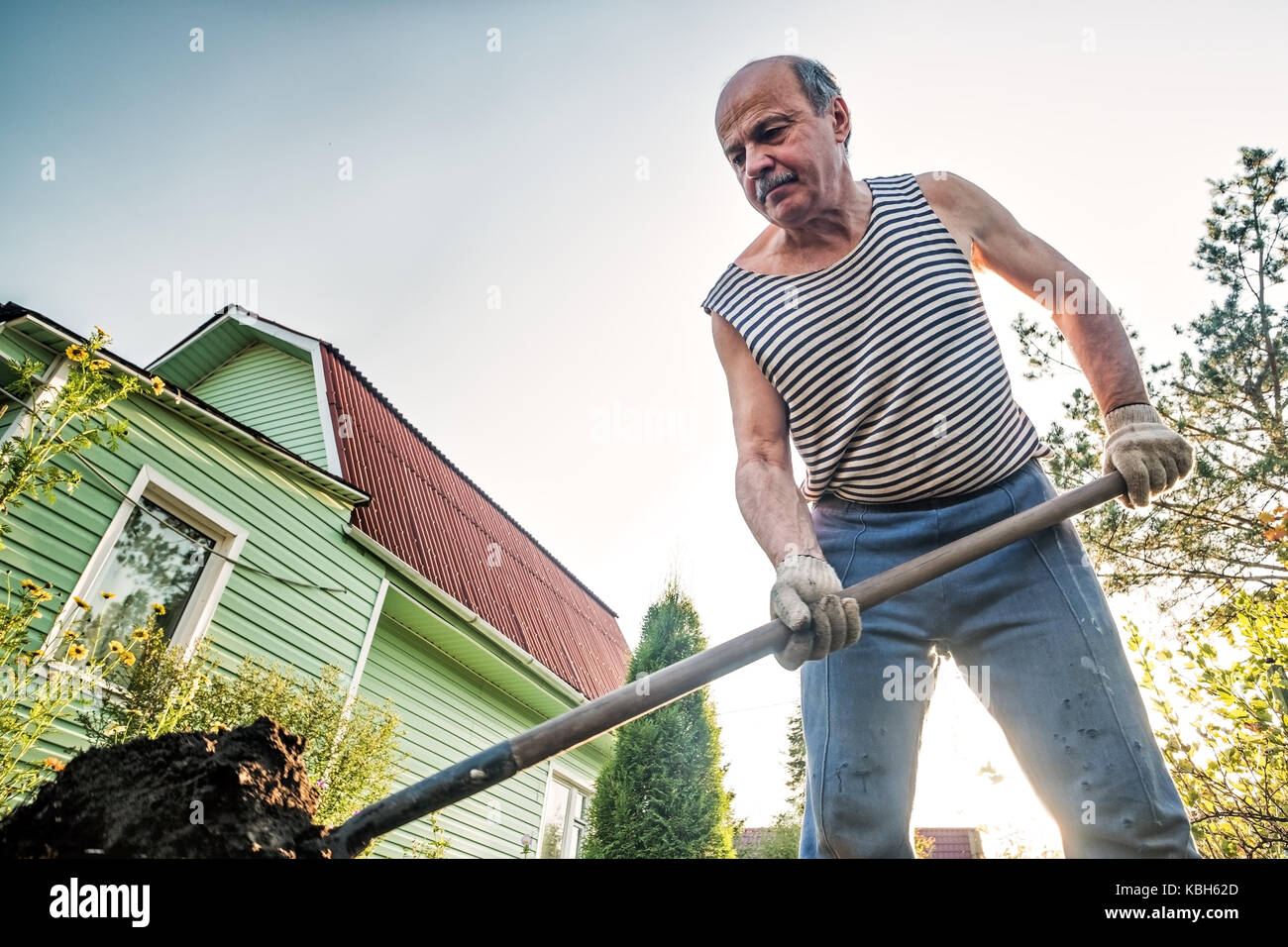 Portrait of caucasian male farmer with shovel digging the land in the ...
