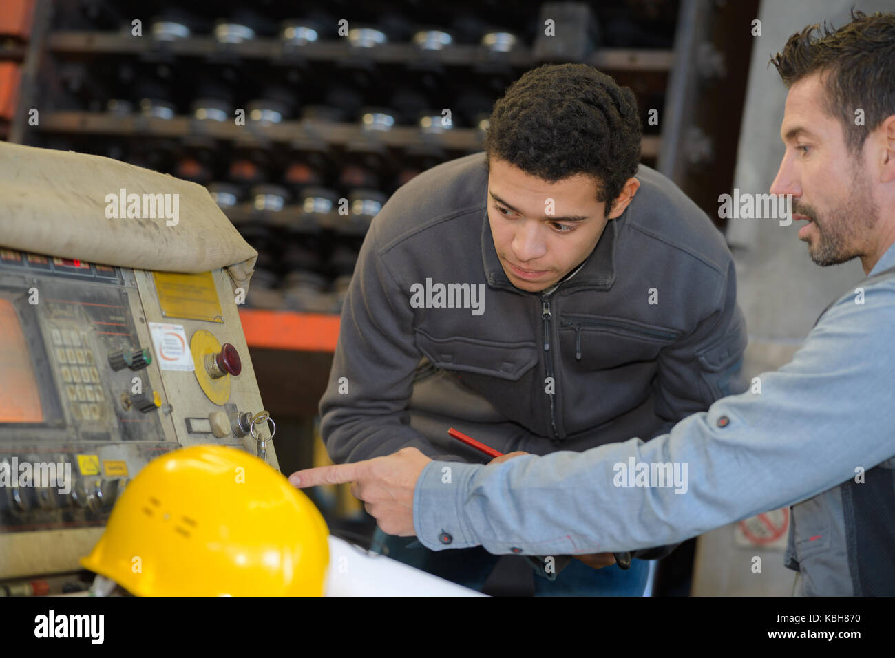 machine operator showing the ropes to a new worker Stock Photo - Alamy