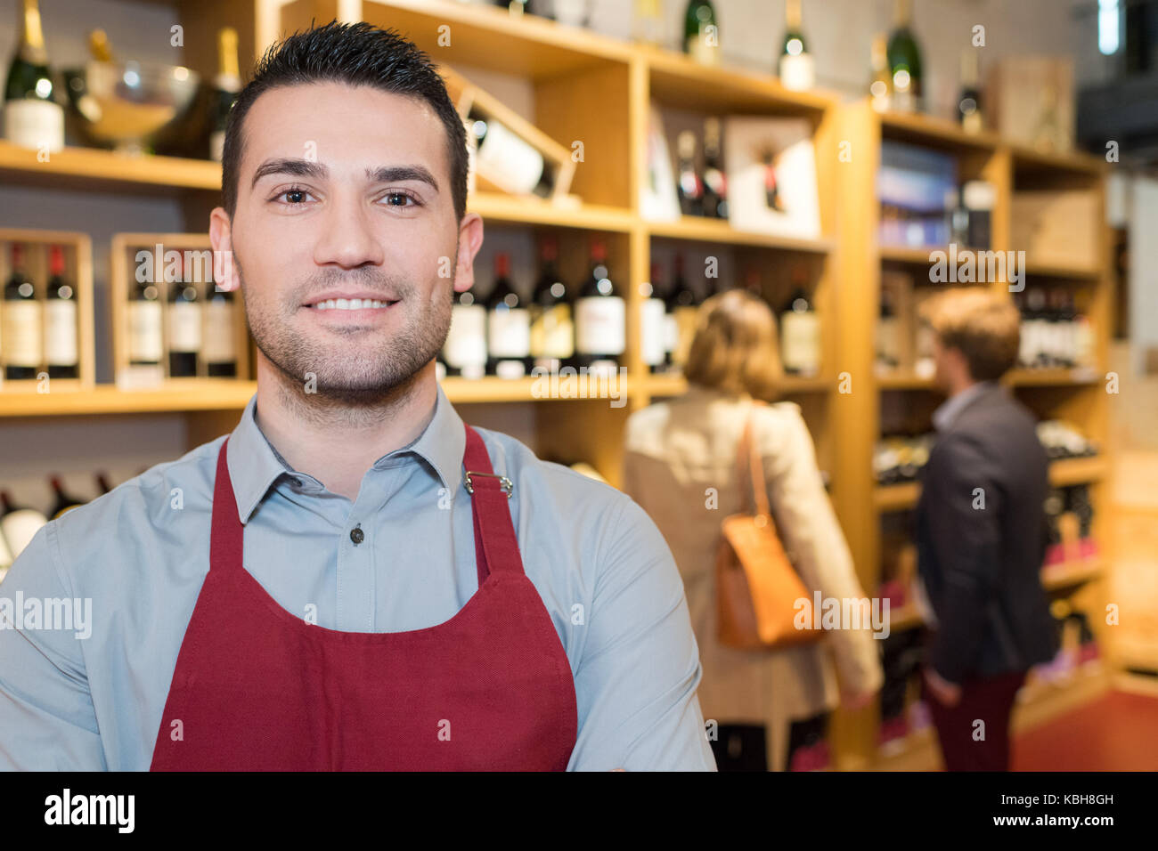 smiling seller man wearing apron in wine store Stock Photo - Alamy