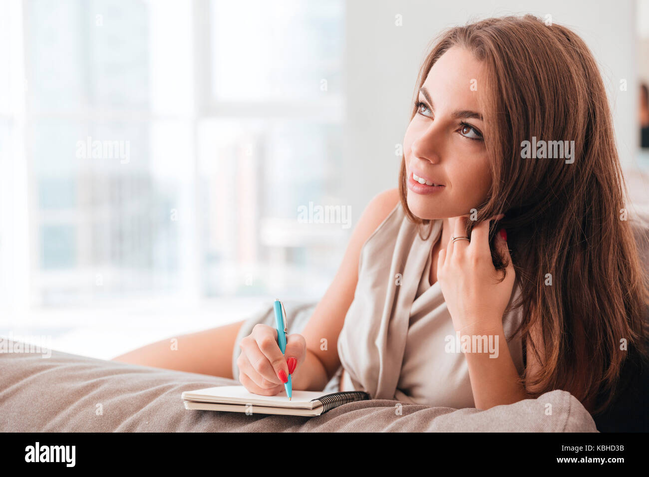 Close up portrait of a smiling pretty woman writing notes in a notepad ...