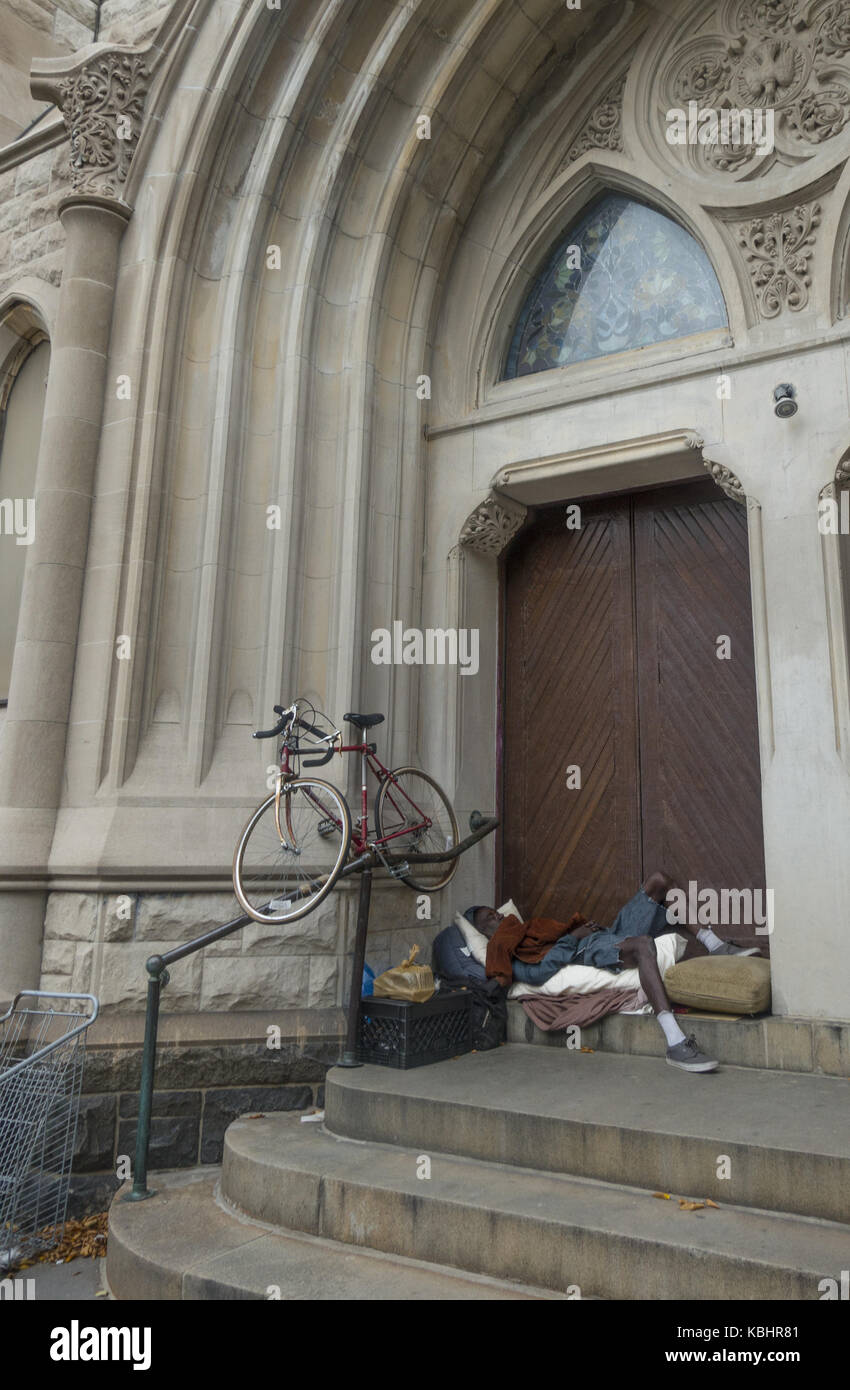 Homeless man with his bicycle sleeps at the entrance of a church on 7th ...