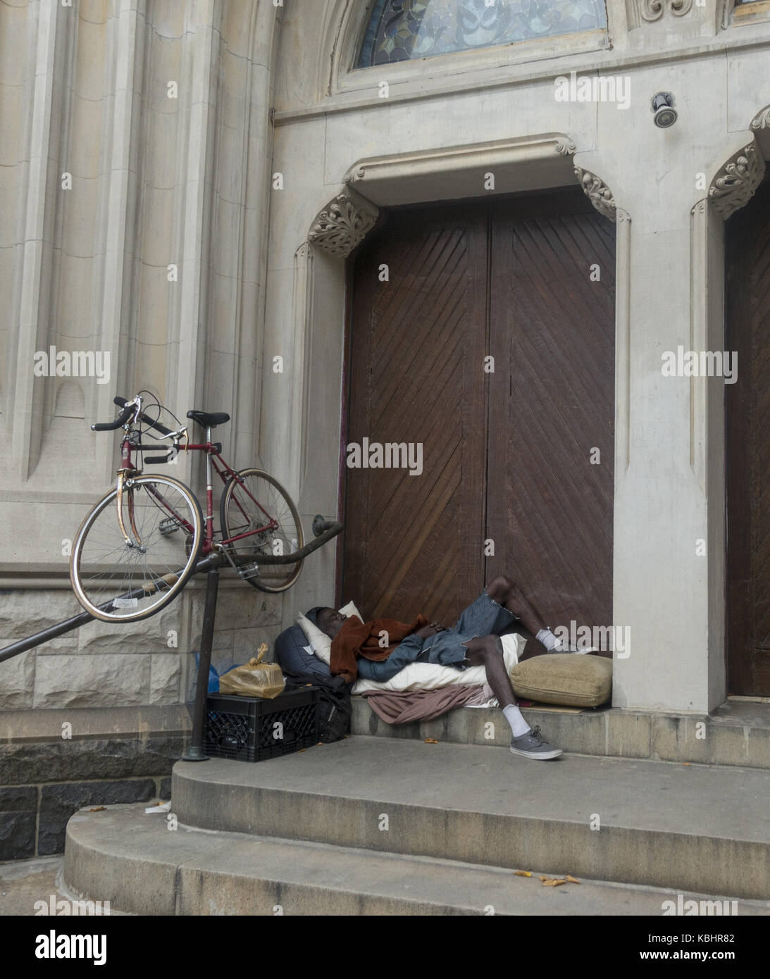Homeless man with his bicycle sleeps at the entrance of a church on 7th ...