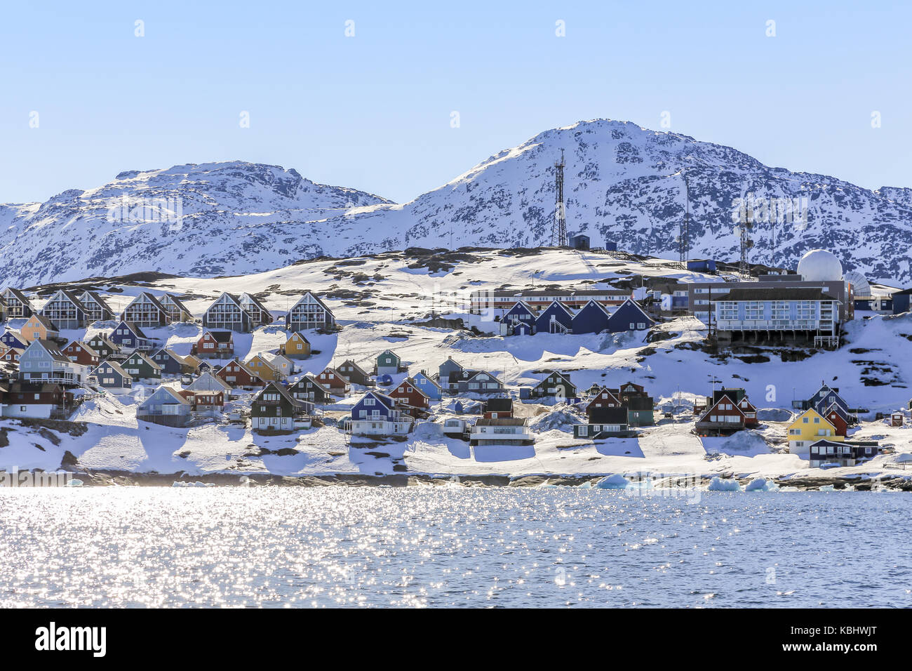 Rows of colorful Inuit houses along the fjord with snow mountains in ...
