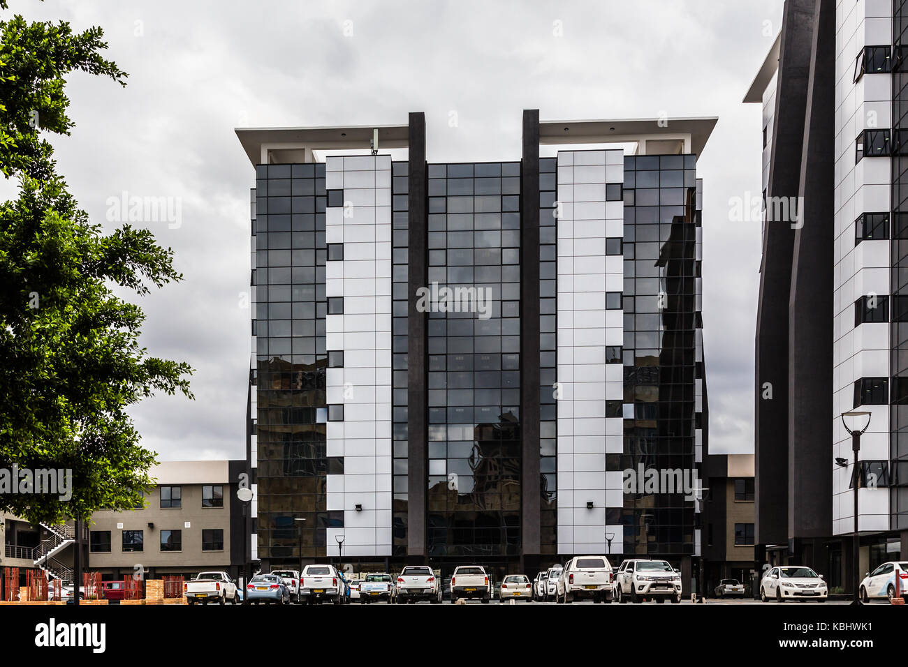 Modern plate glass building and parking lot with cars in central ...