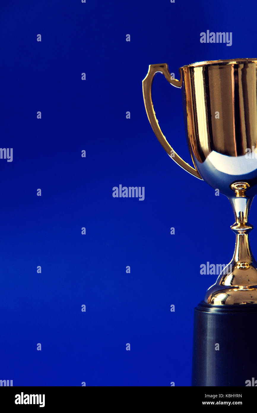 Gold winners trophy cup on a blue background Stock Photo - Alamy