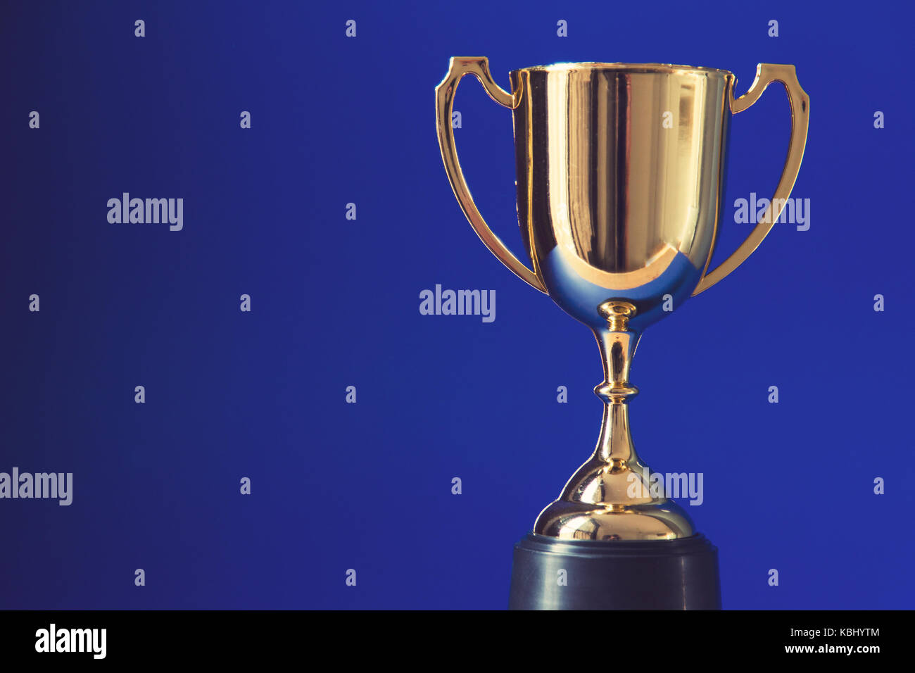 Gold winners trophy cup on a blue background Stock Photo - Alamy