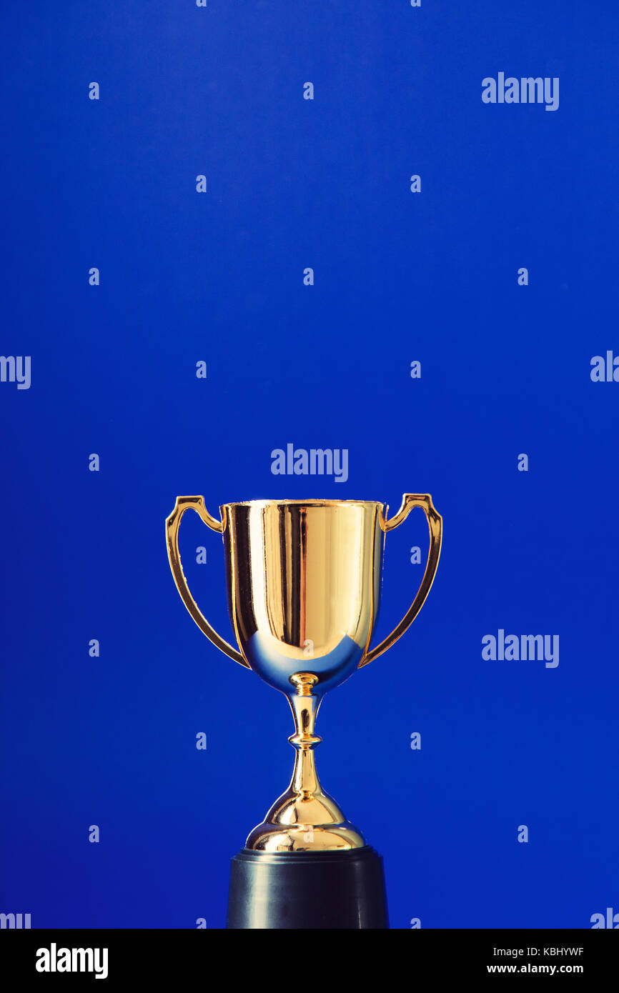 Gold winners trophy cup on a blue background Stock Photo - Alamy