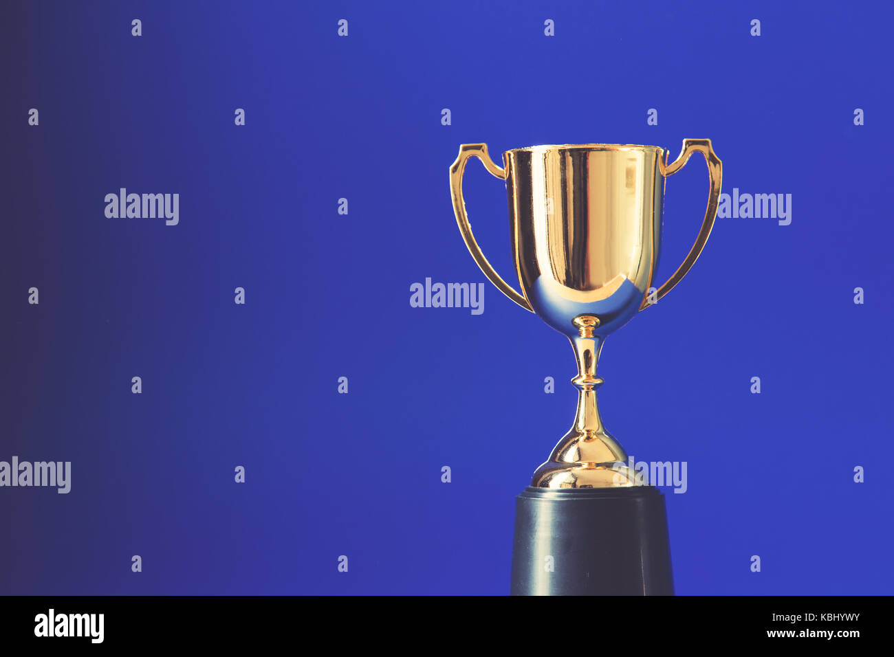 Gold winners trophy cup on a blue background Stock Photo - Alamy