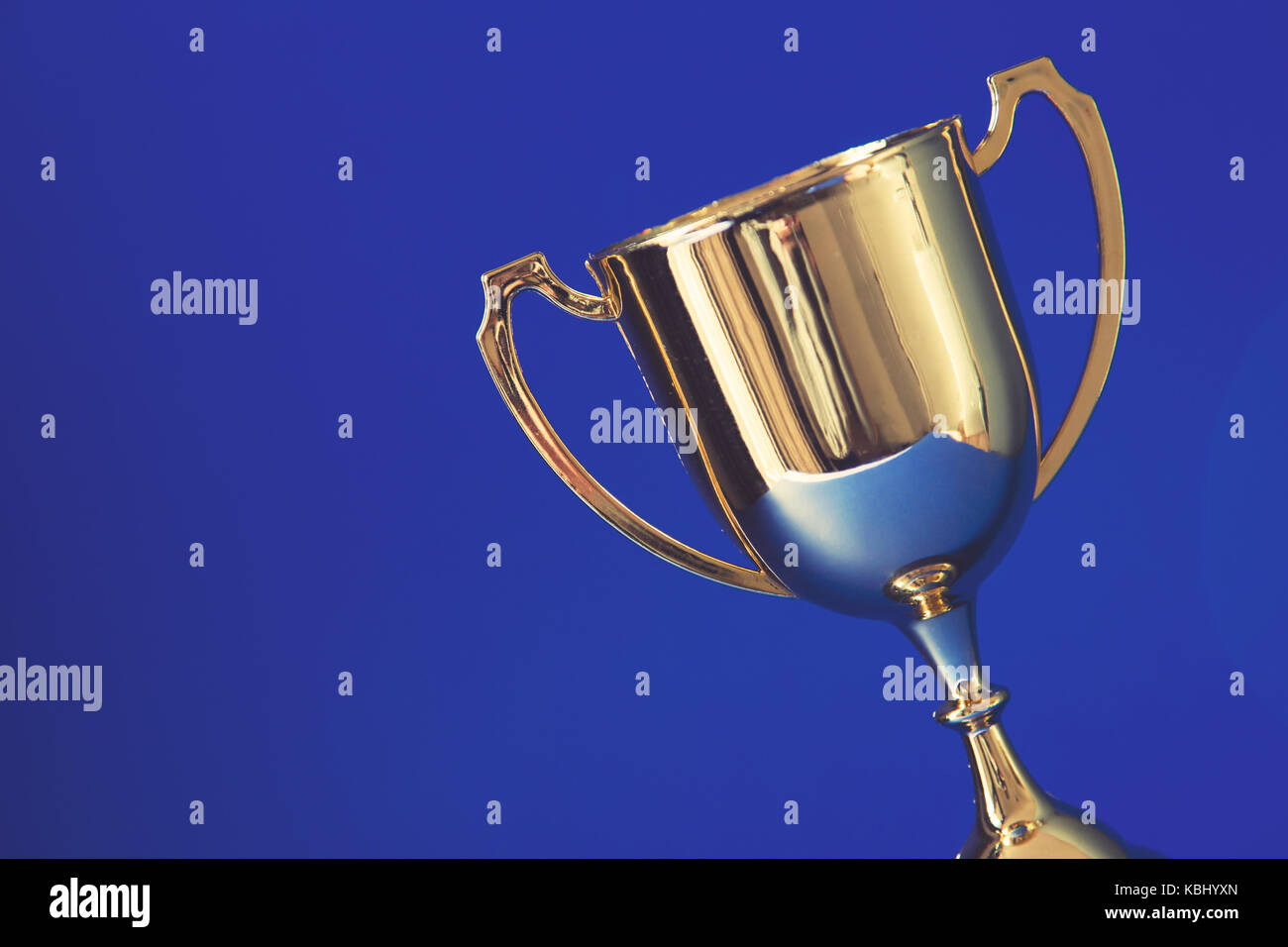 Gold winners trophy cup on a blue background Stock Photo - Alamy