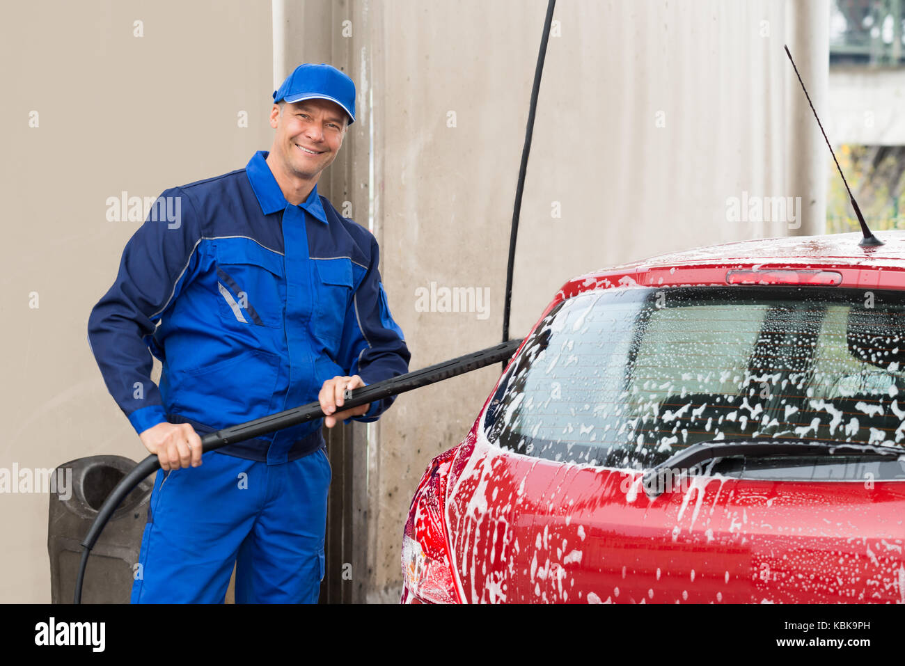 Portrait of confident male worker washing red car at garage Stock Photo ...