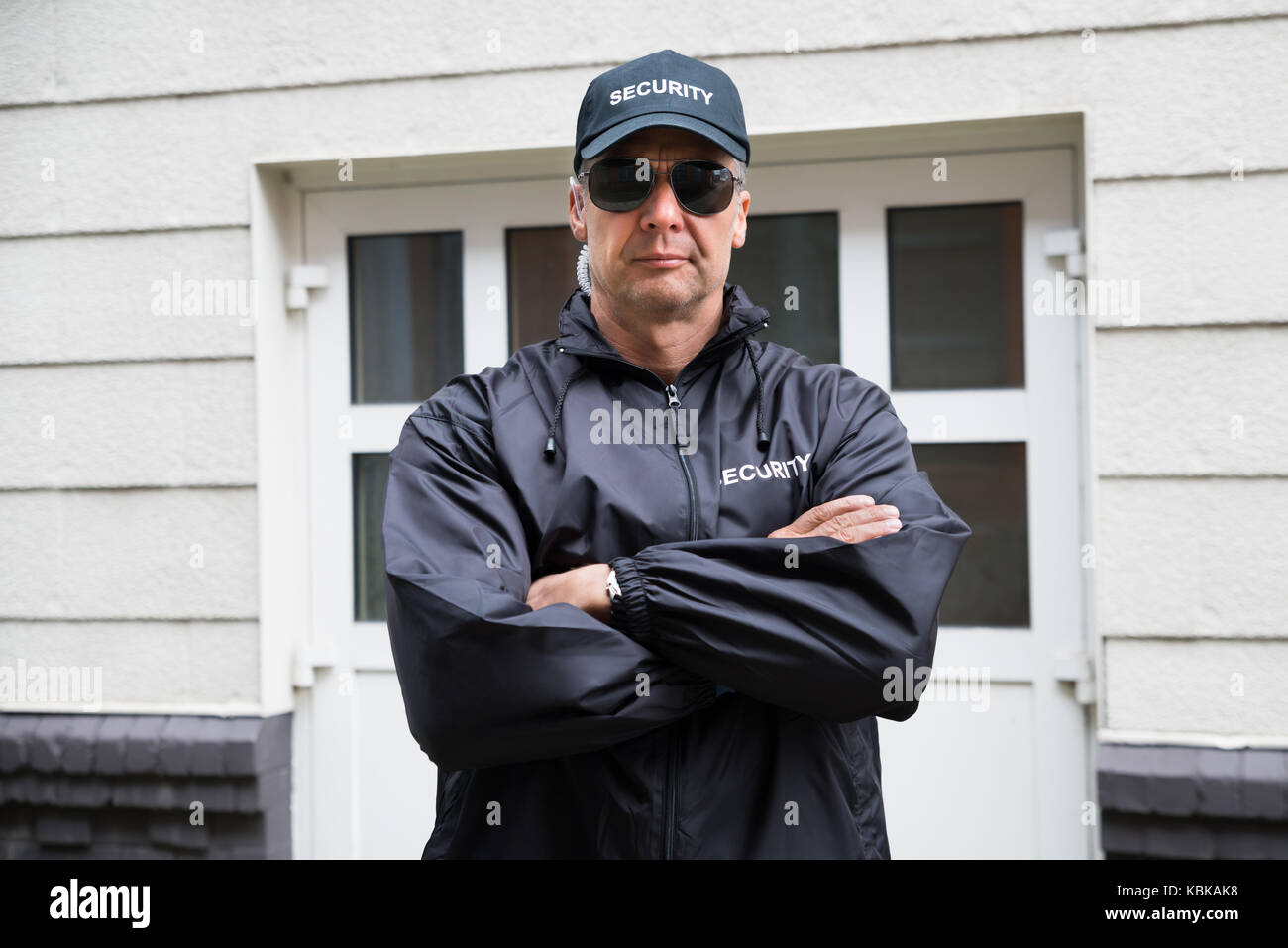 Portrait of confident mature security guard standing arms crossed ...