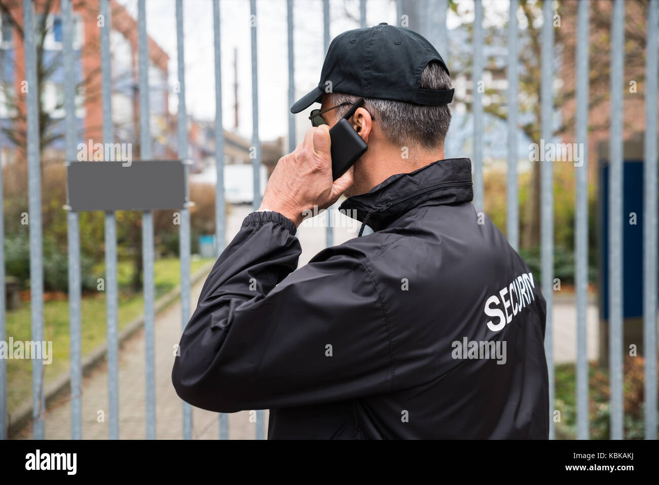 Confident mature security guard talking on mobile phone in front of ...