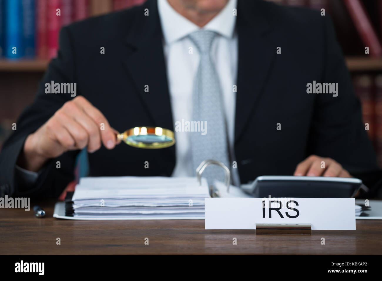 Midsection of tax auditor examining documents with magnifying glass at ...