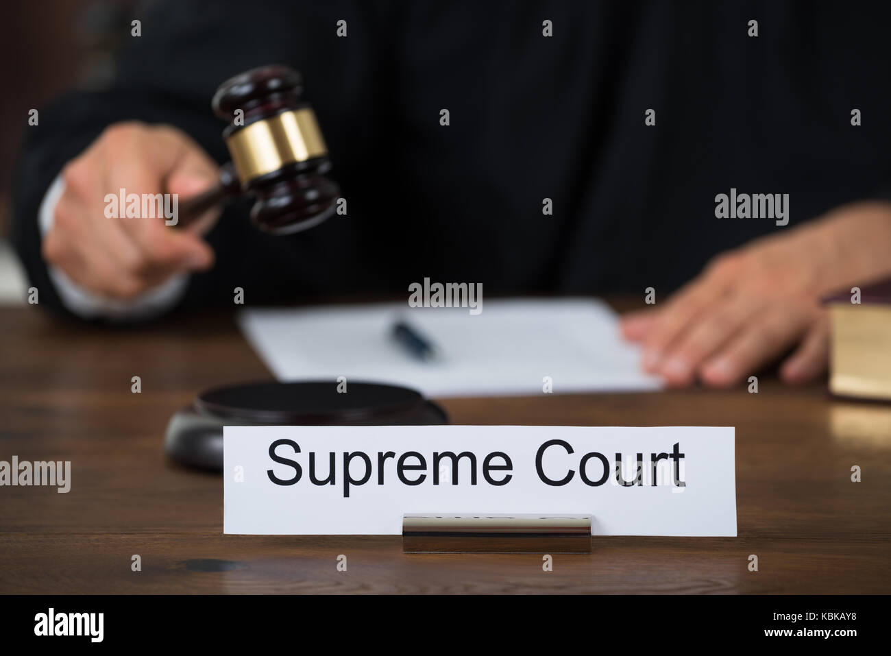 Supreme court nameplate with judge writing on paper at table in ...