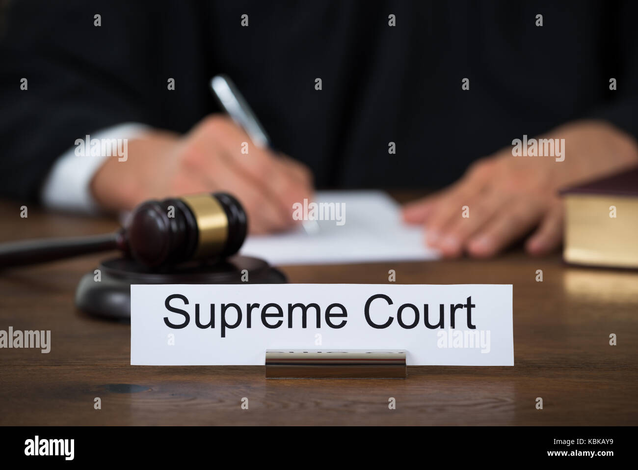 Supreme court nameplate with judge writing on paper at table in ...