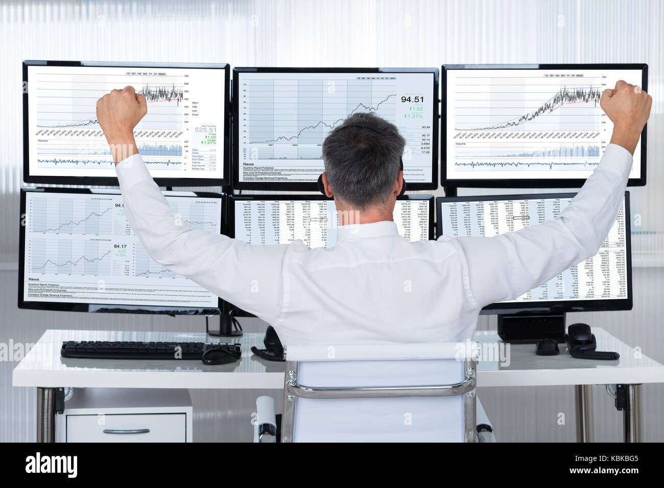 Rear view of successful stock market trader looking at graphs on ...