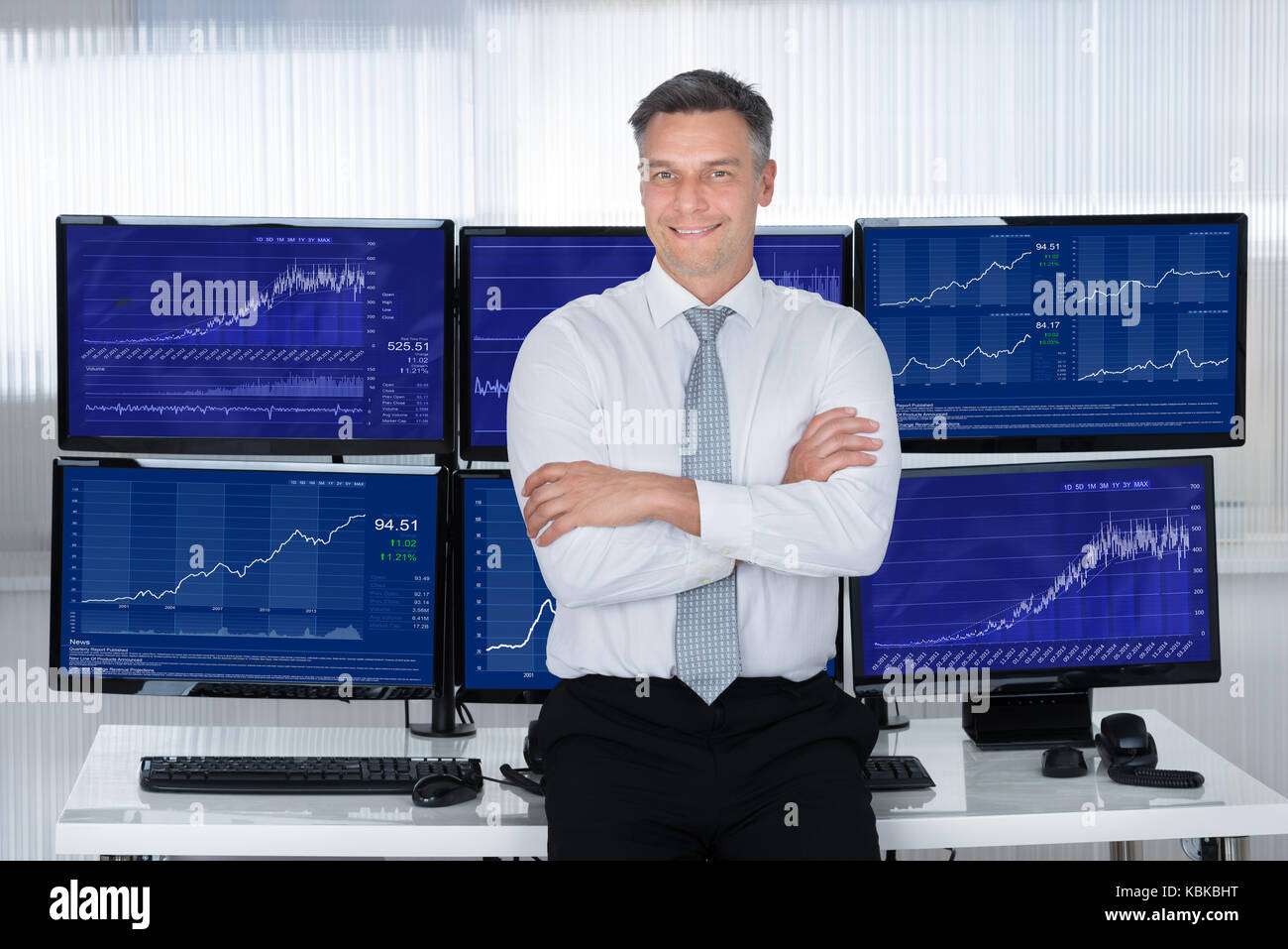 Portrait of confident stock market broker leaning on desk at office ...