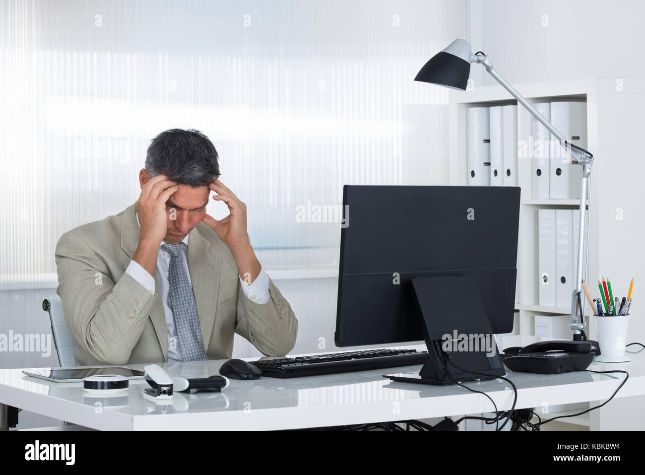 Mature businessman suffering from headache at desk in office Stock ...