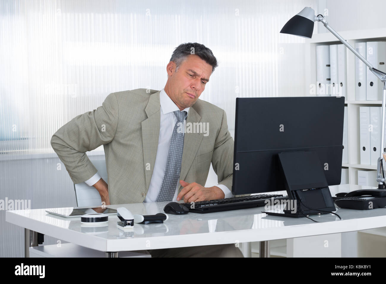 Mature businessman suffering from back pain at desk in office Stock ...