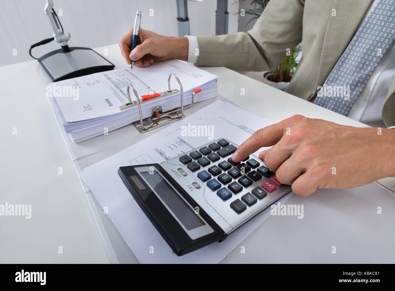 Midsection of accountant calculating bills at desk in office Stock ...