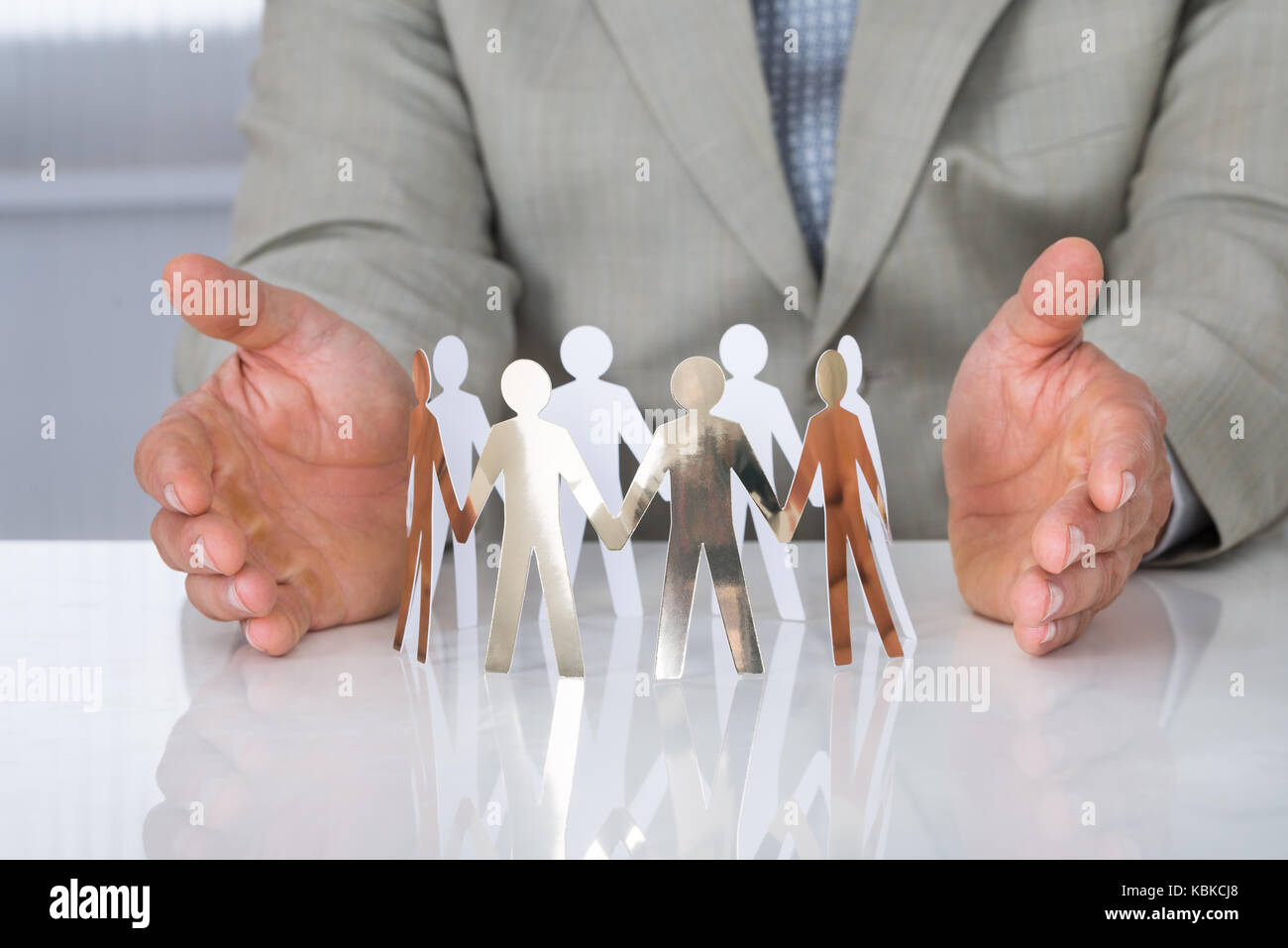 Midsection of businessman protecting paper team on desk in office Stock ...