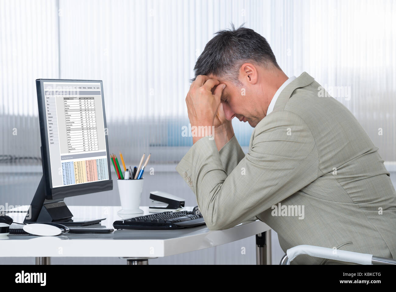 Side view of accountant suffering from headache at desk in office Stock ...