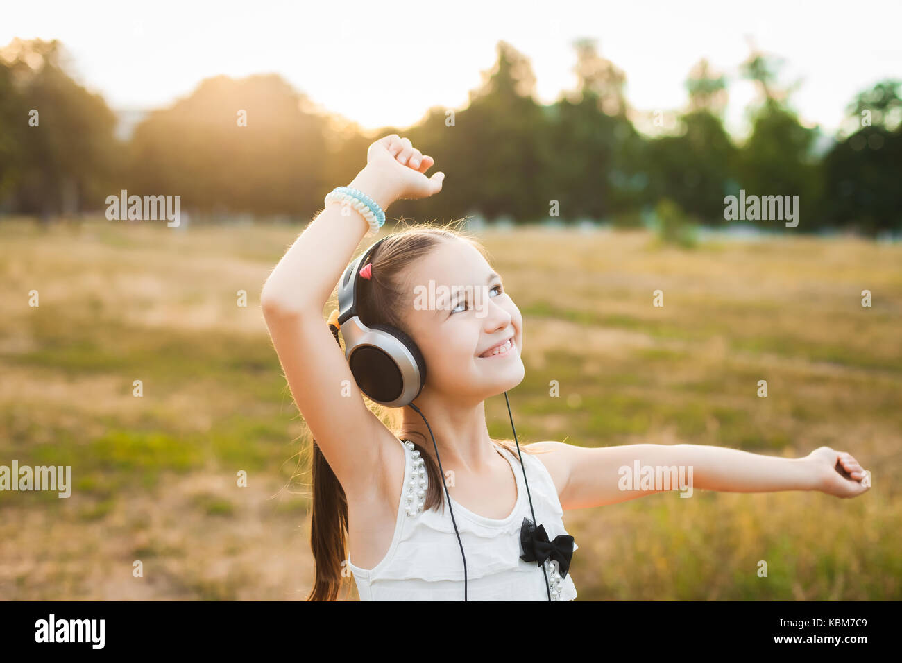 joyful girl having fun in the field, kindly child with black and silver ...