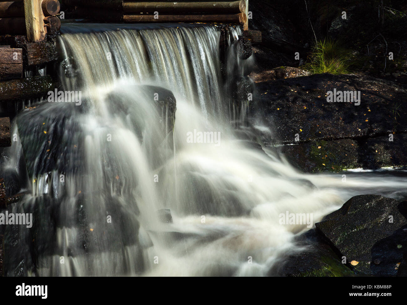 A waterfall at a dam, pond. Building to the left Stock Photo - Alamy