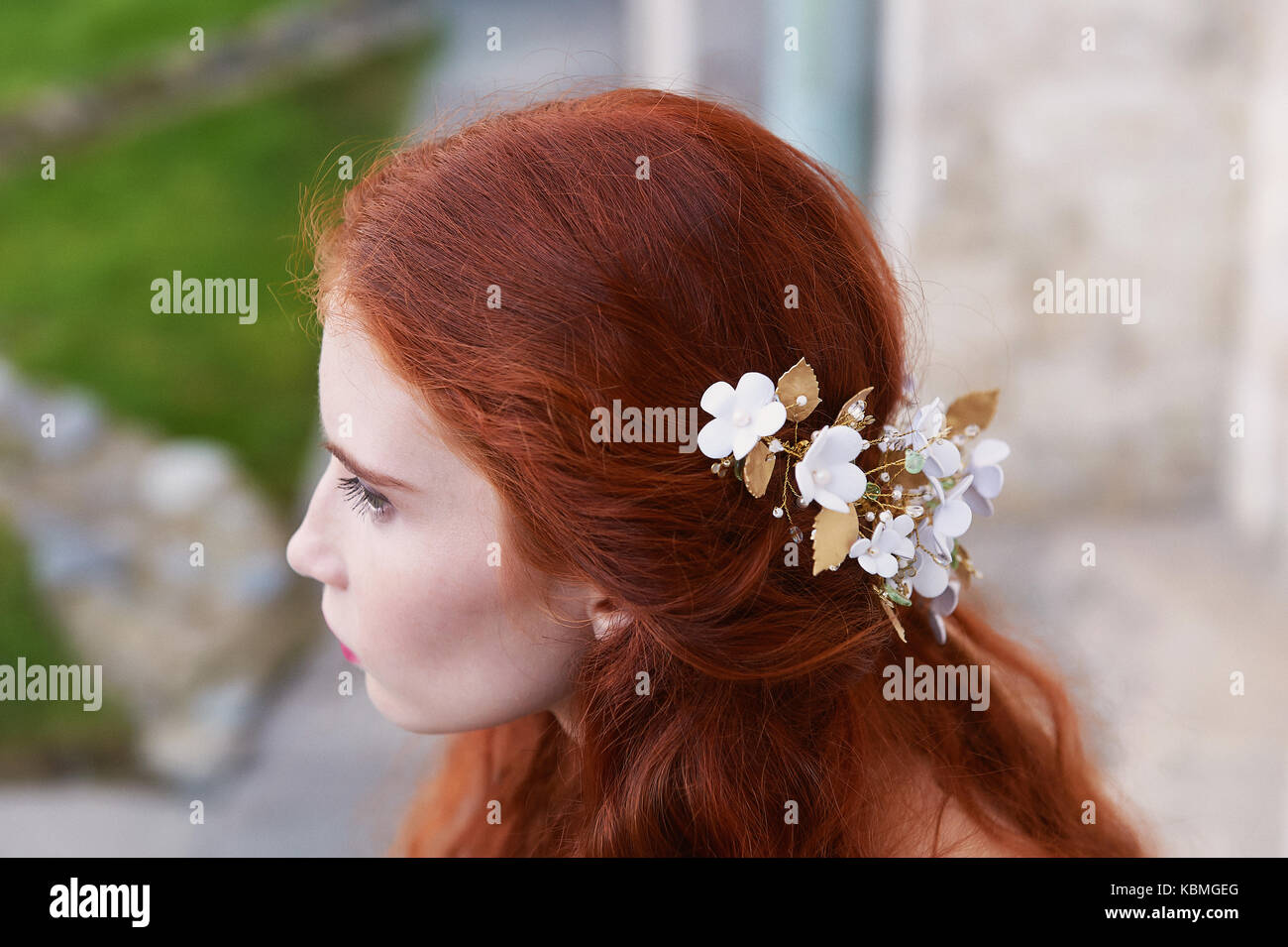 Beautiful red-haired bride sits back .Slightly visible profile. Long ...
