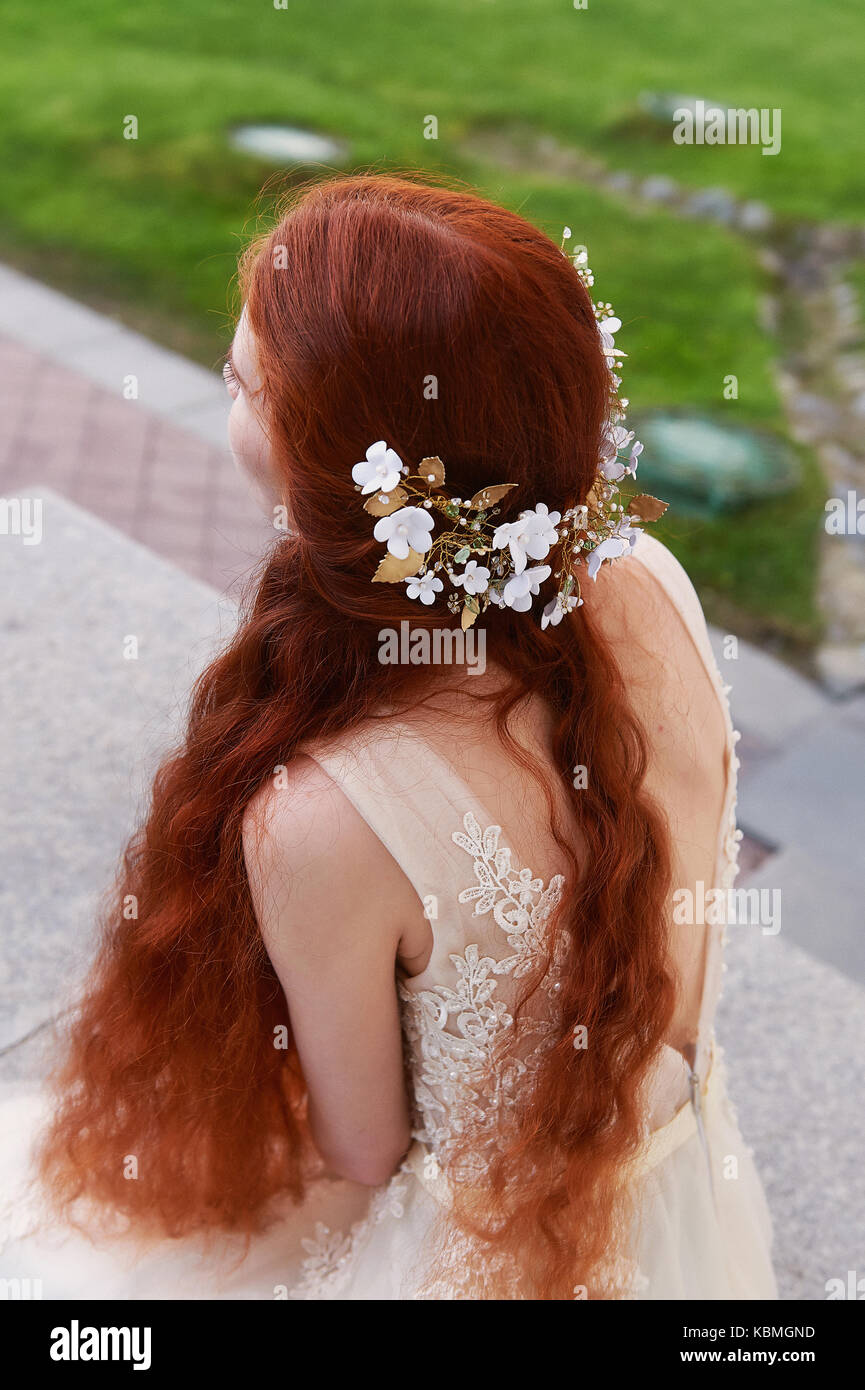Beautiful red-haired bride sits back .Slightly visible profile. Long ...