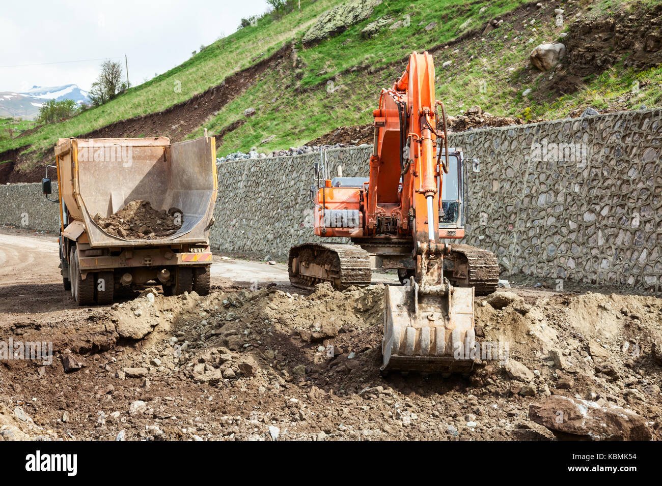 Excavator loading dirt into a truck at road construstion site Stock ...