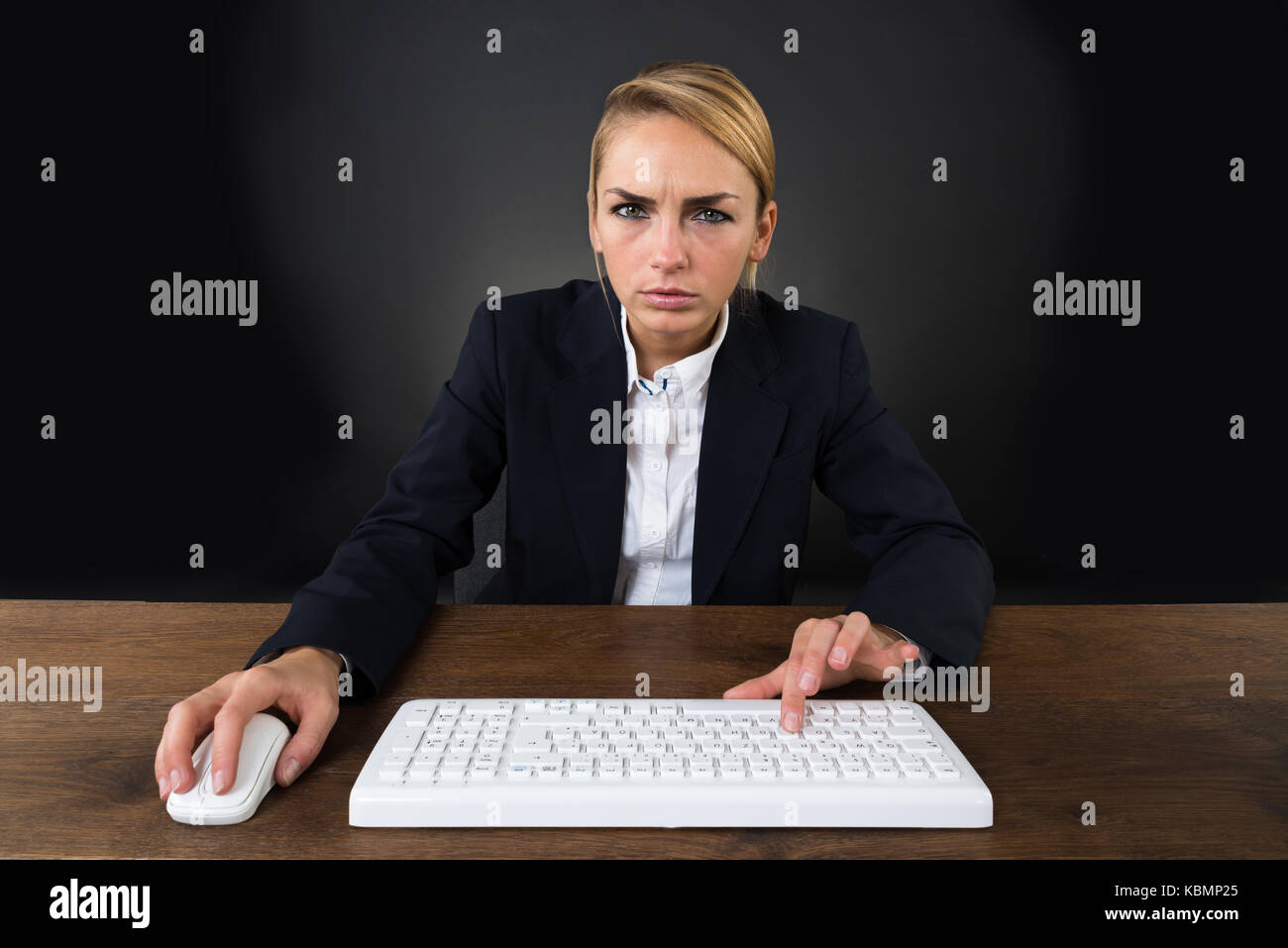 Portrait of serious young businesswoman using computer mouse and ...