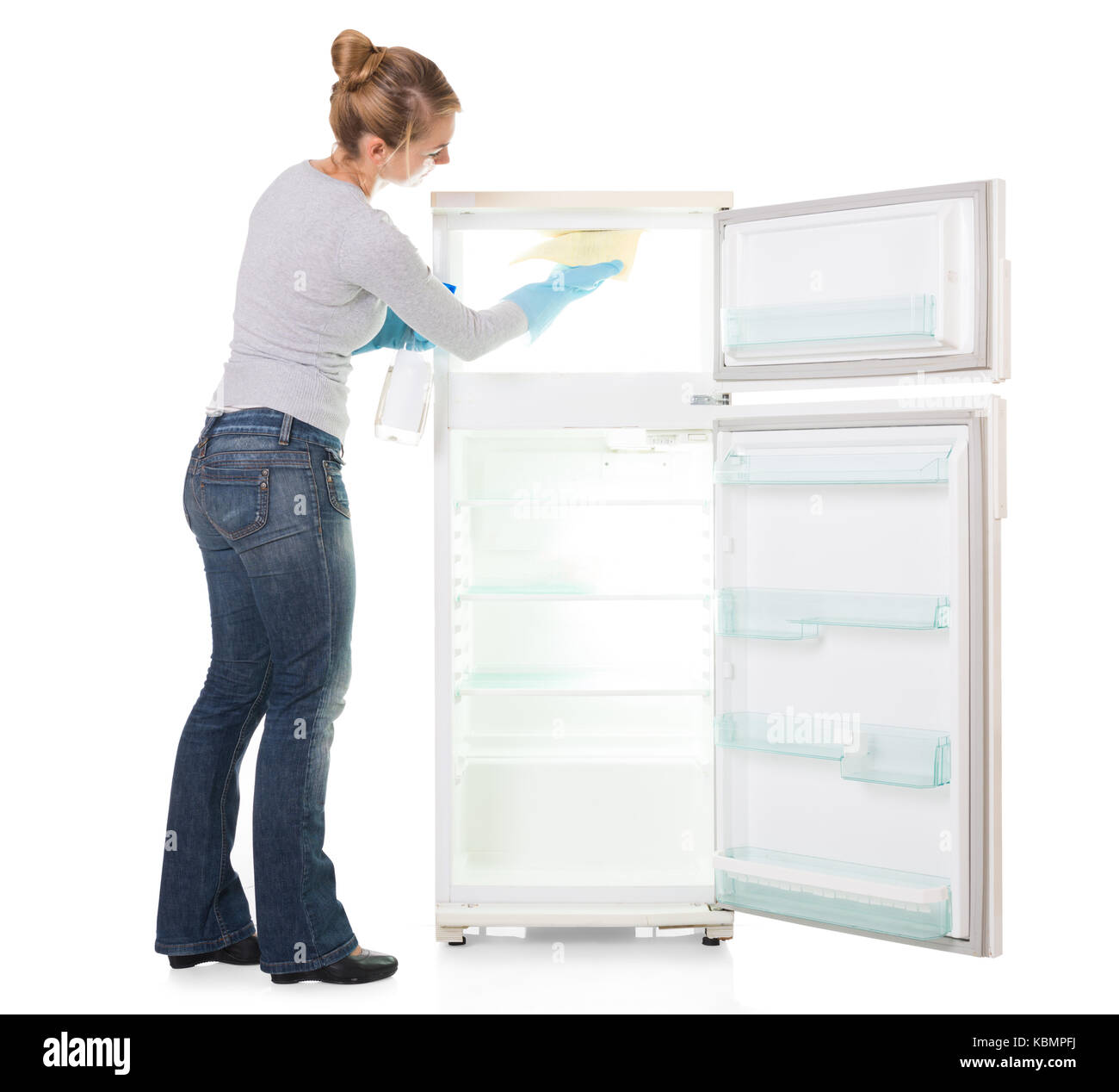 Full length of young woman cleaning refrigerator over white background ...