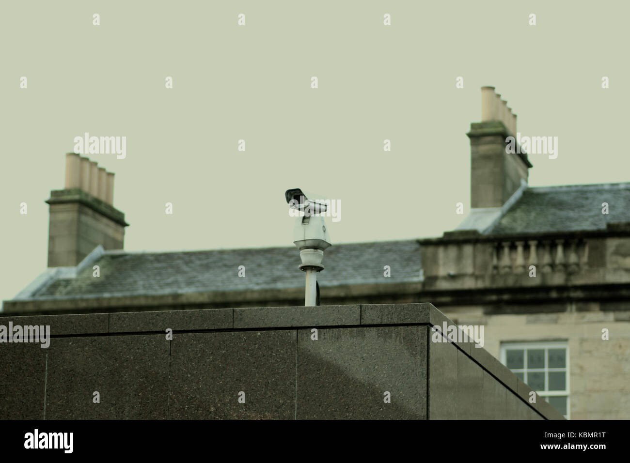 CCTV camera perched on top of a public building looking down, with ...