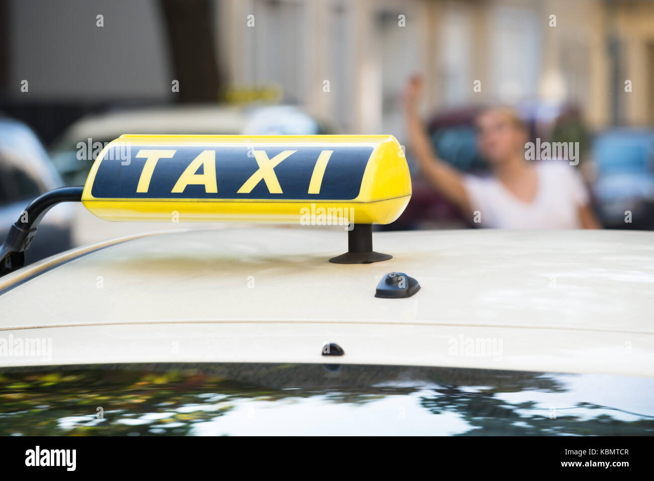 Young woman raising arm to hail taxi on street Stock Photo - Alamy